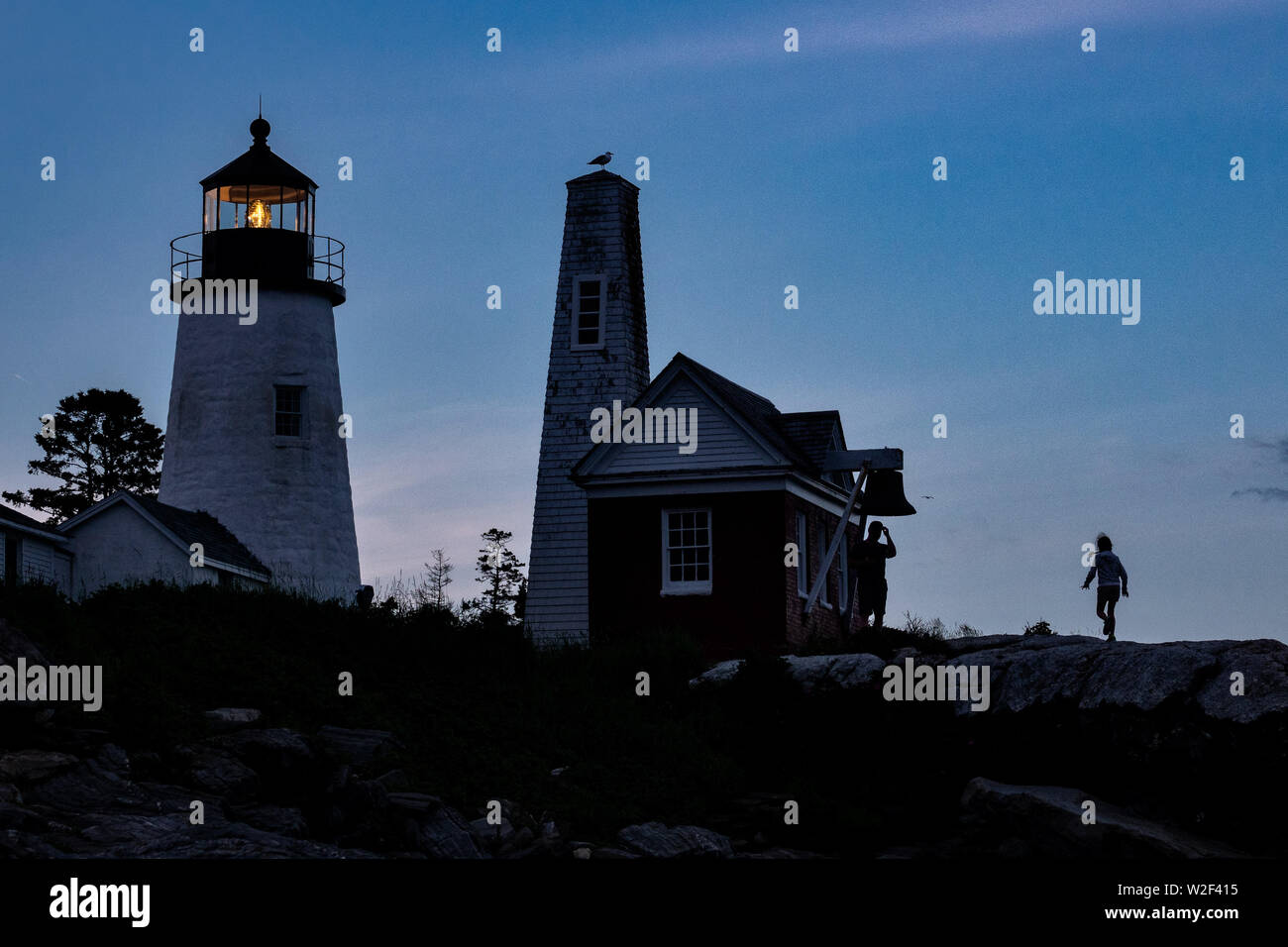 Children silhouetted by the setting sun at the historic Pemaquid Point ...