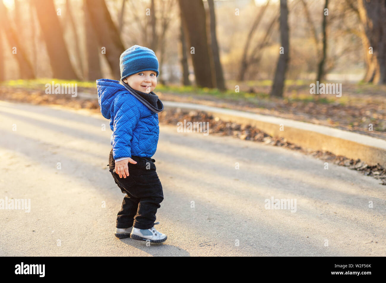 Portrait of cute funny caucasian toddler boy in blue jacket and hat ...