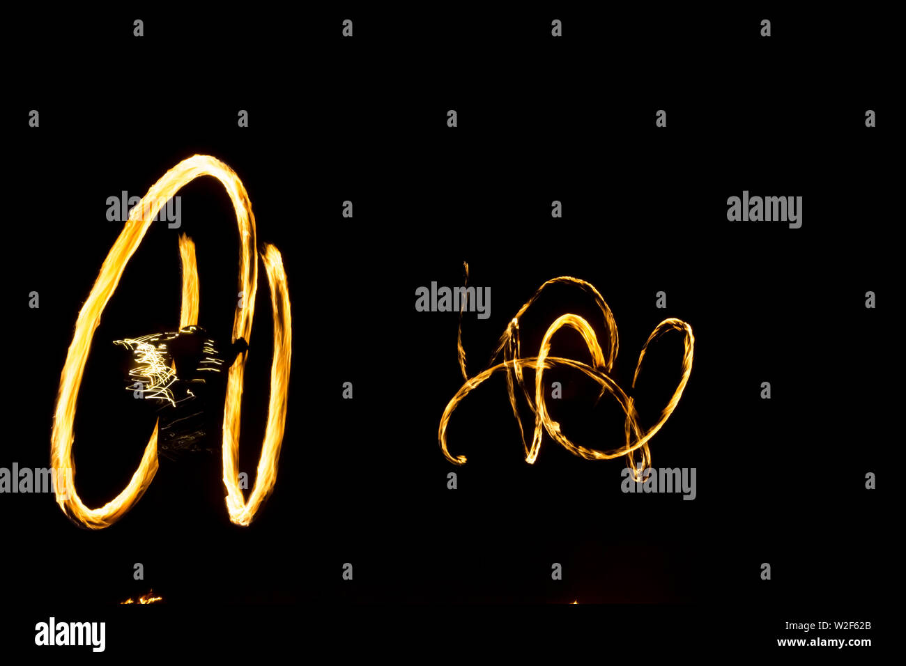 An artist shows a fire show at night spinning torches, circles of fire ...