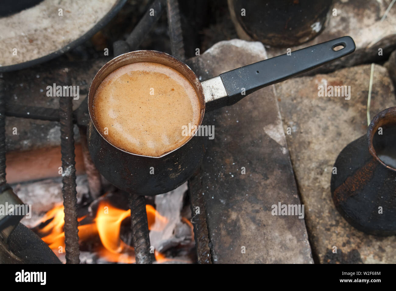 Boiling coffee in turkish cezva on a grate over a burning bonfire ...