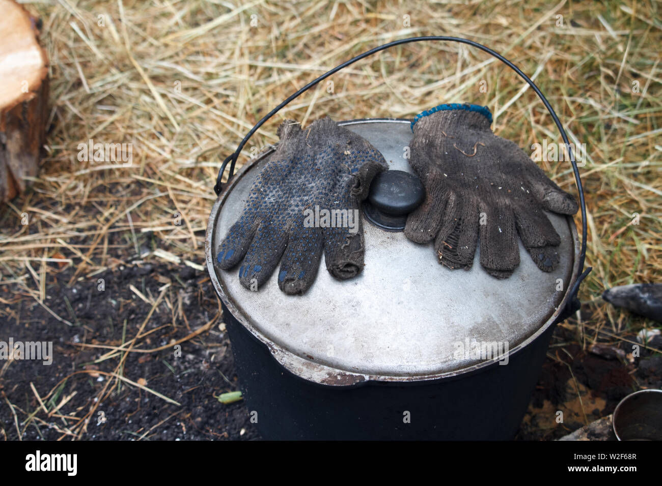 A gloves in soot are on the lid of a pot with ready-made food near the ...