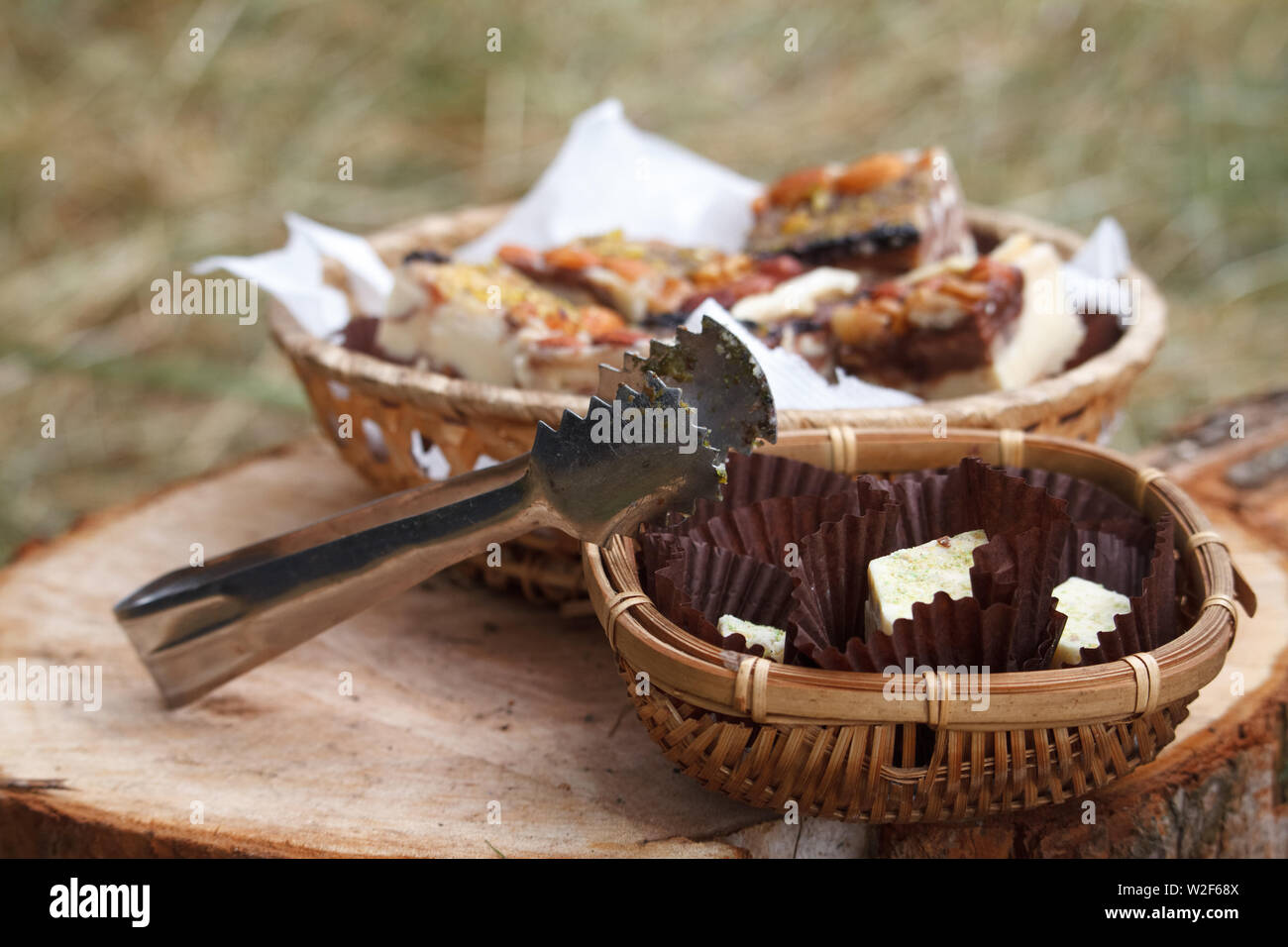 Closeup oriental sweets in two wicker baskets and tongs for serving ...