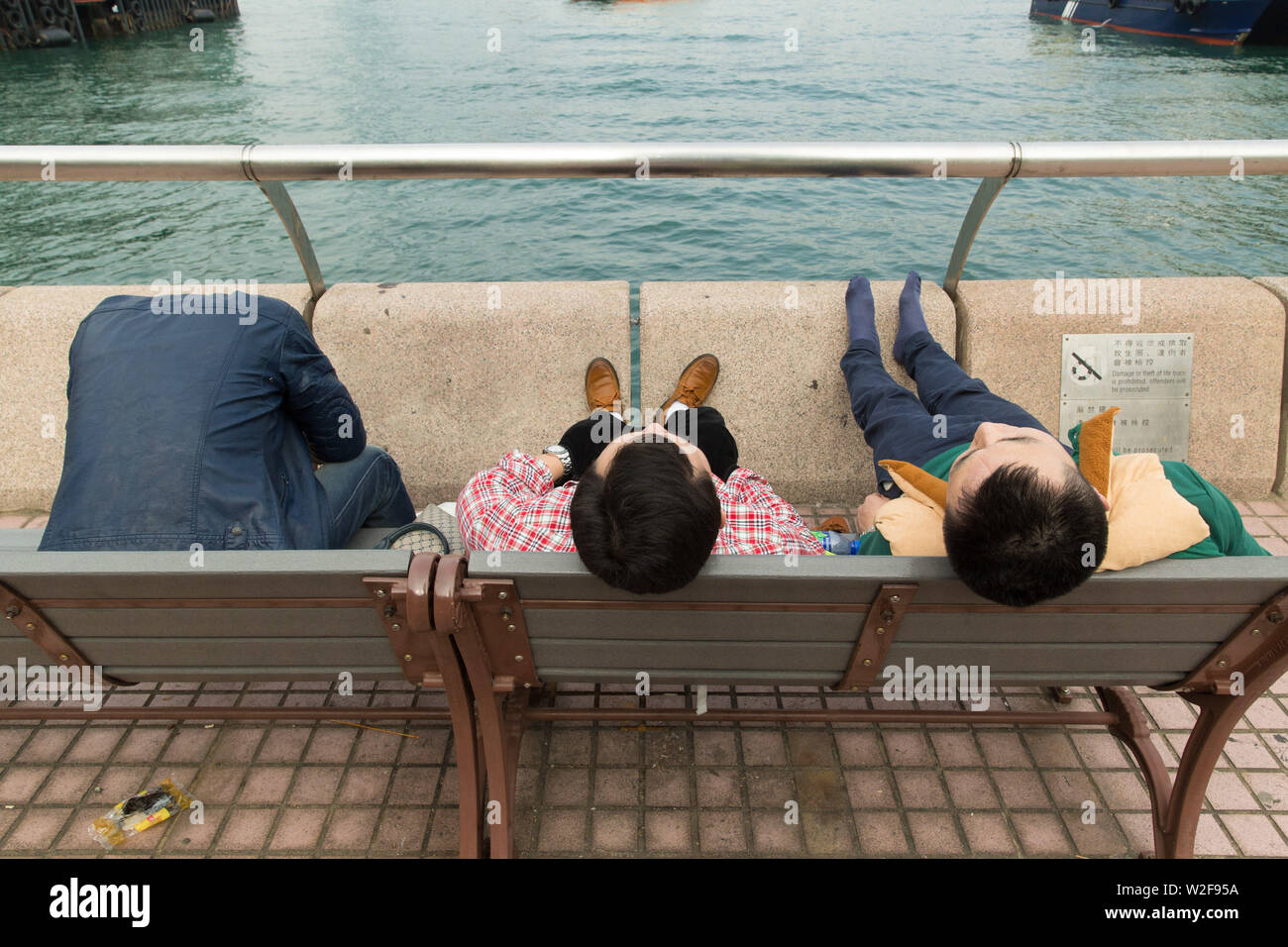 three men taking a nap sleeping on a bench by Victoria Harbour Stock ...