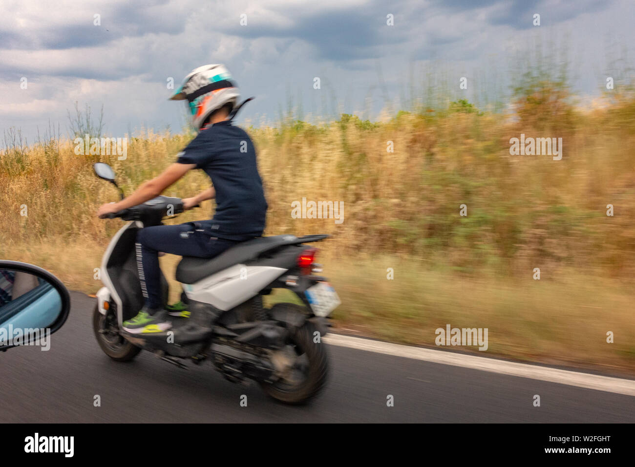 Blurred with movement photograph of Young scooter rider riding fast and ...