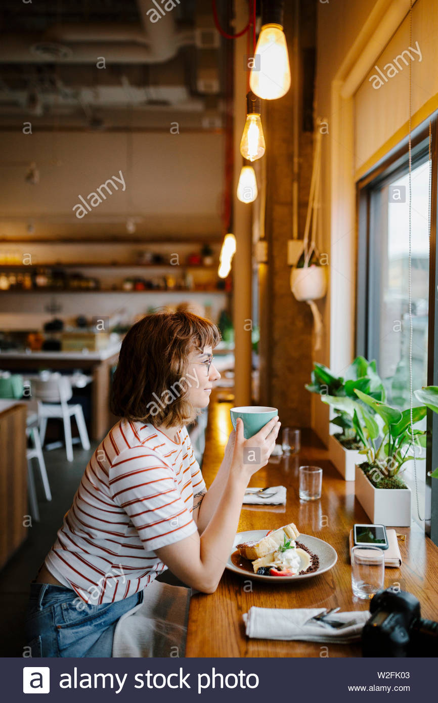 Confident young woman dining at counter in restaurant Stock Photo - Alamy