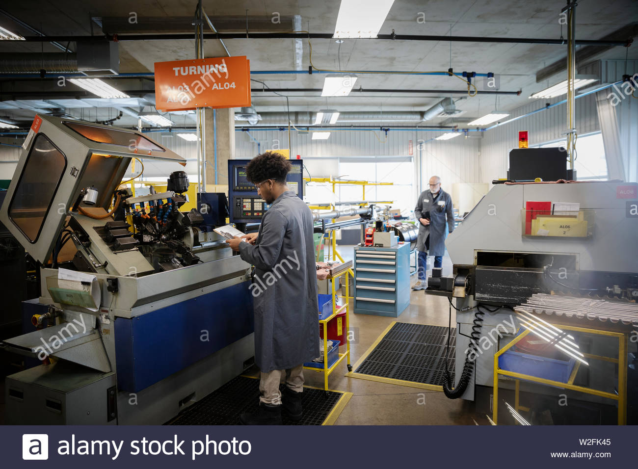 Machinists operating machinery in factory Stock Photo - Alamy