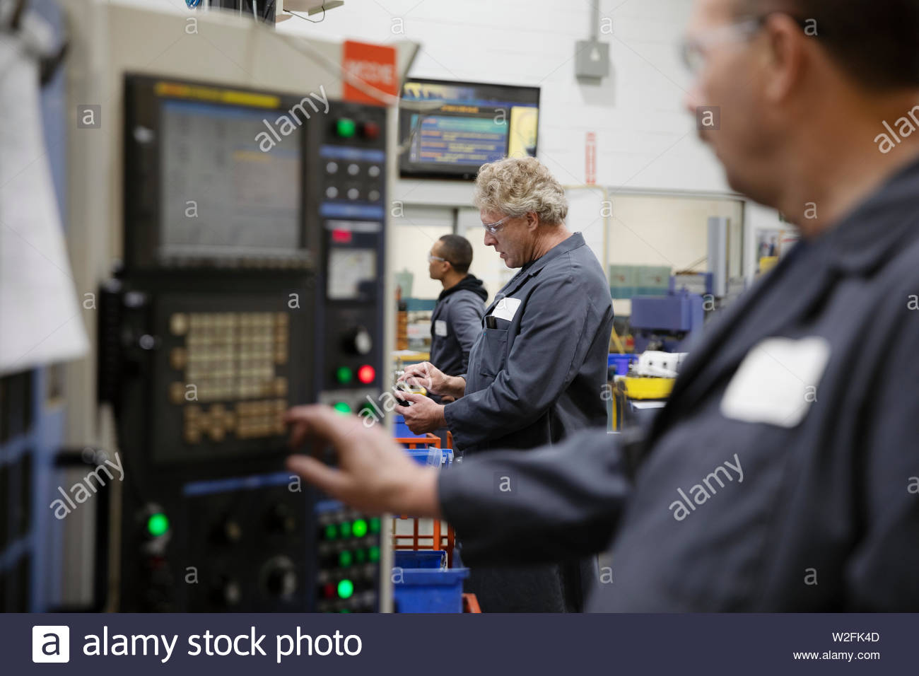 Male machinists operating machinery in factory Stock Photo - Alamy