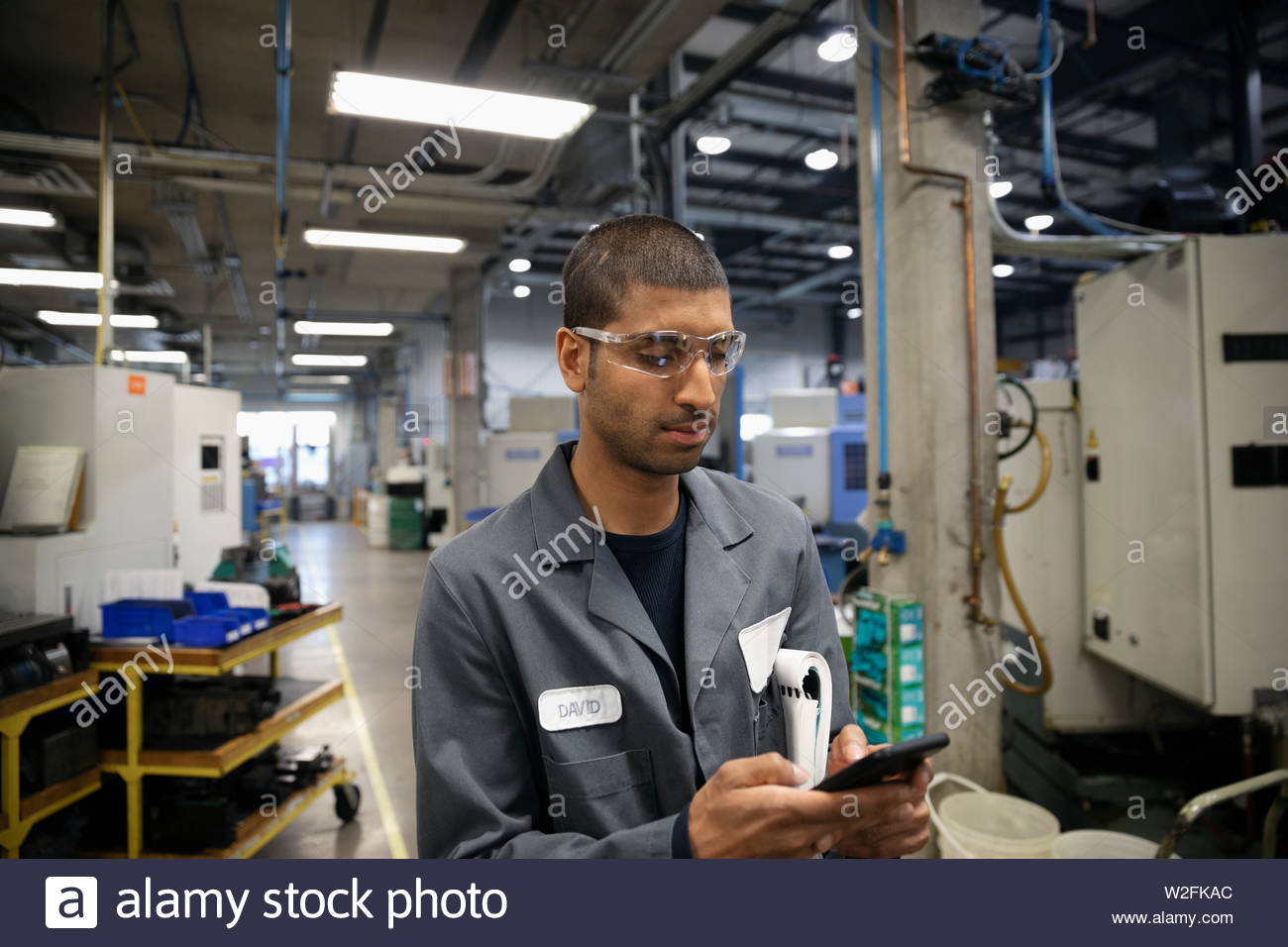 Male machinist using smart phone in factory Stock Photo - Alamy