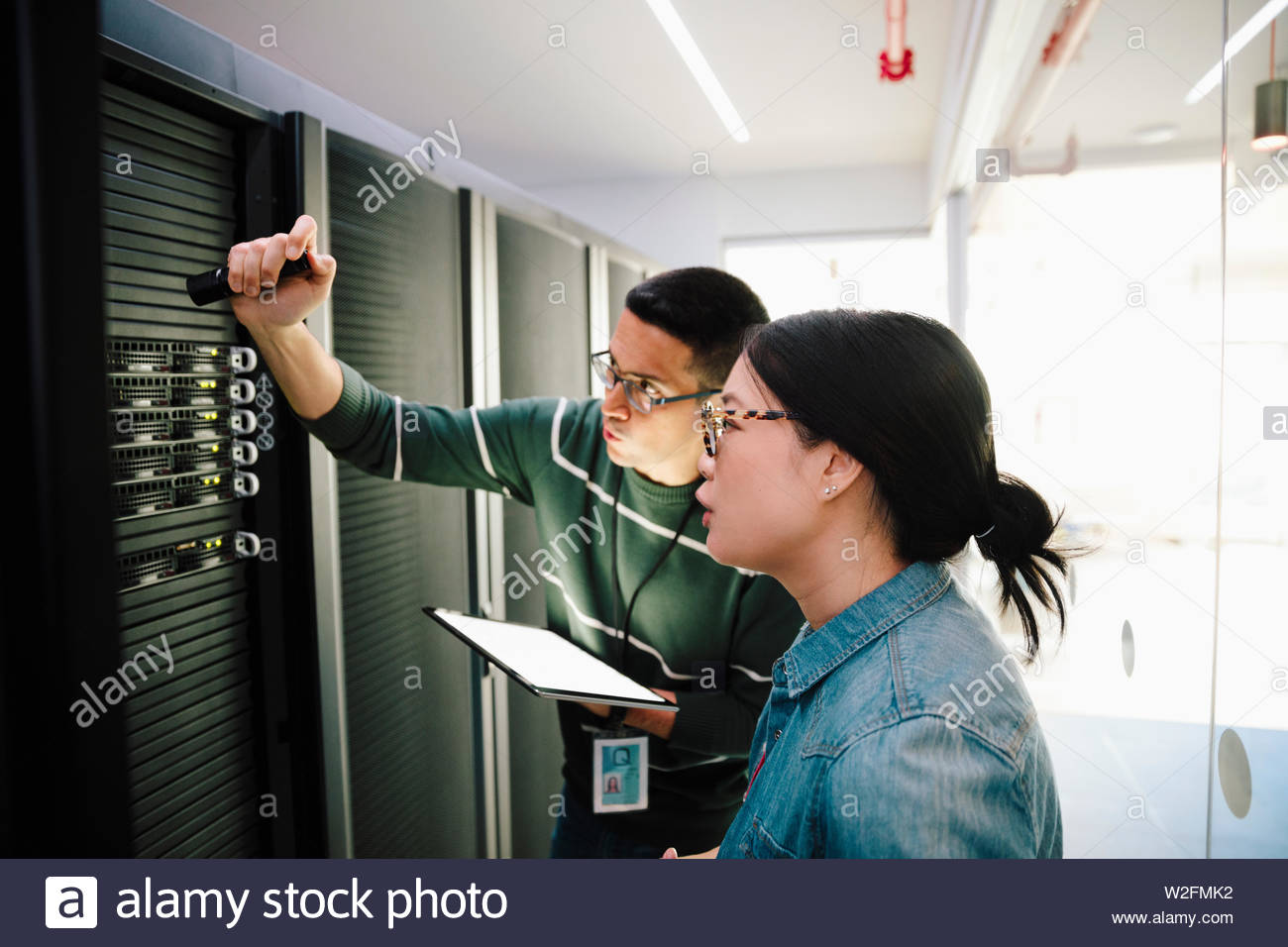 IT technicians with flashlight talking in network server room Stock ...
