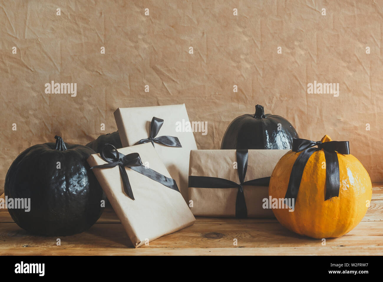 Halloween gift box with ribbons and pumpkins on wooden table. Holiday ...