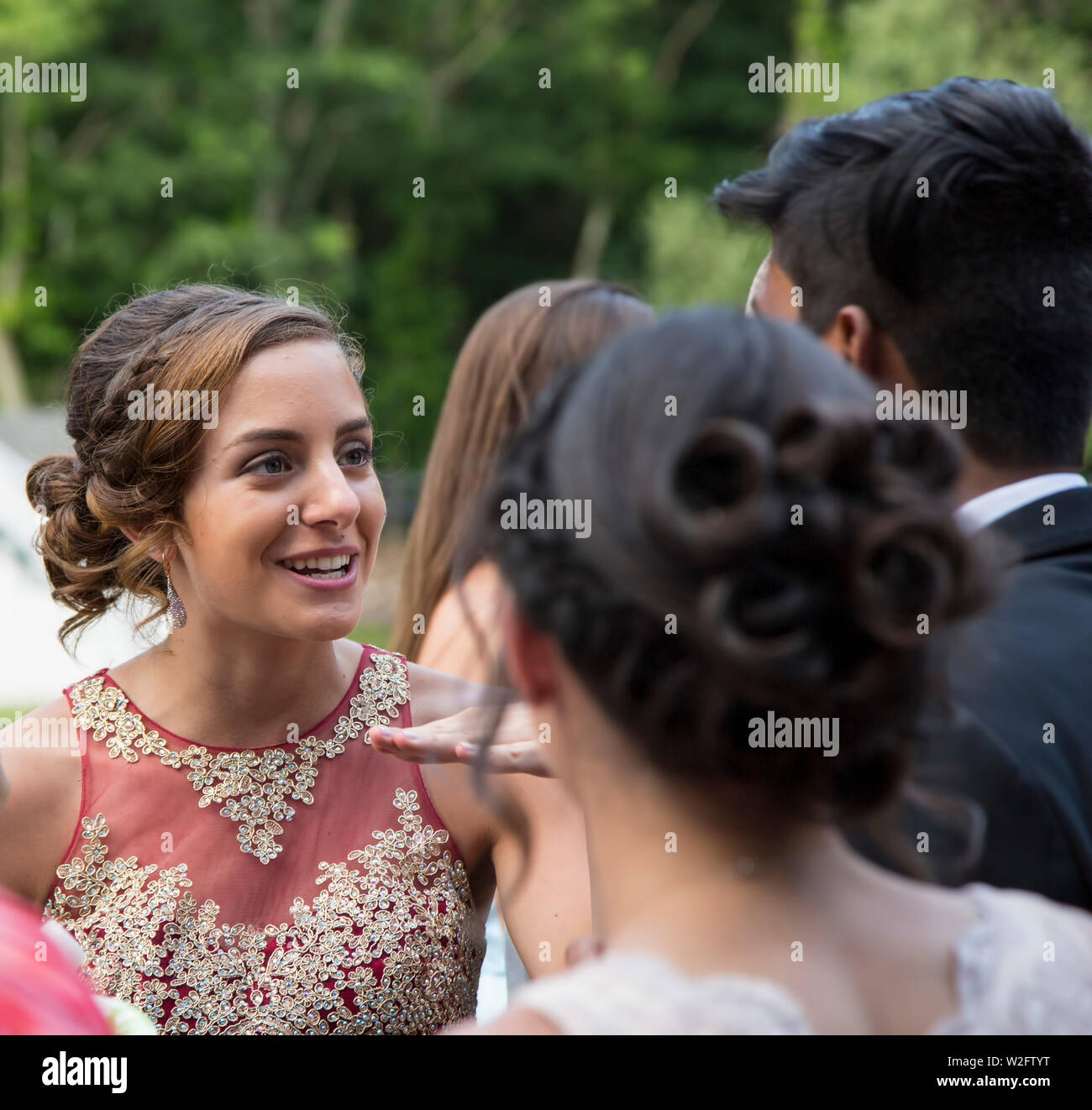 Girl in formal gown talking with friends and getting ready for prom ...