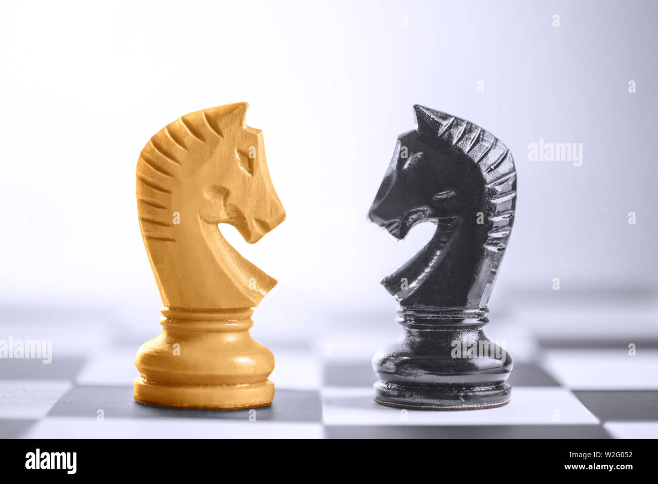 Brown knight chess piece standing face black knight chess piece on the ...