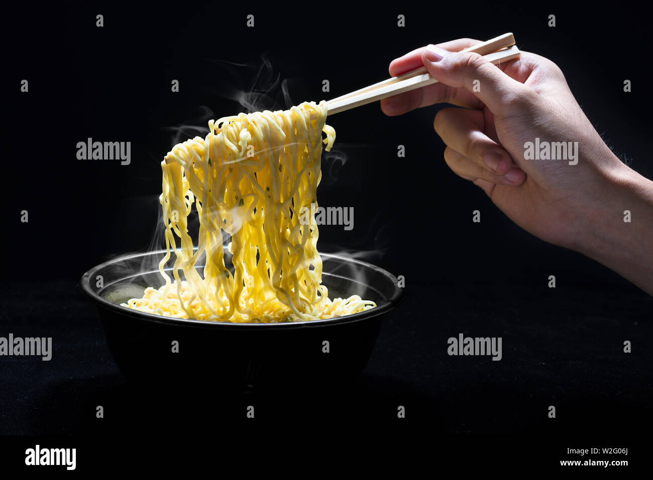 People eat the noodles with chopsticks over black background Stock ...