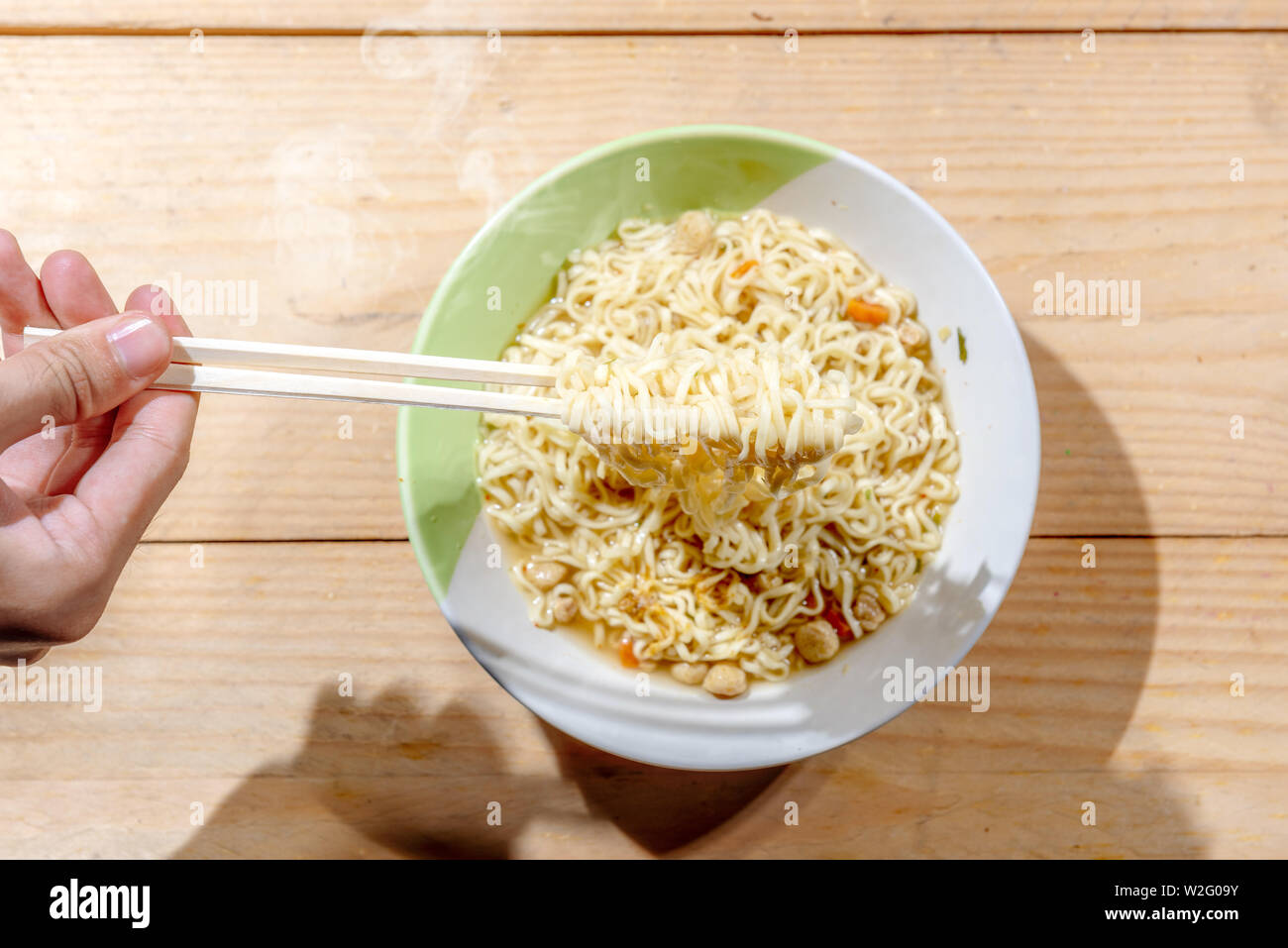 People eat the noodles with chopsticks on wooden table background Stock ...