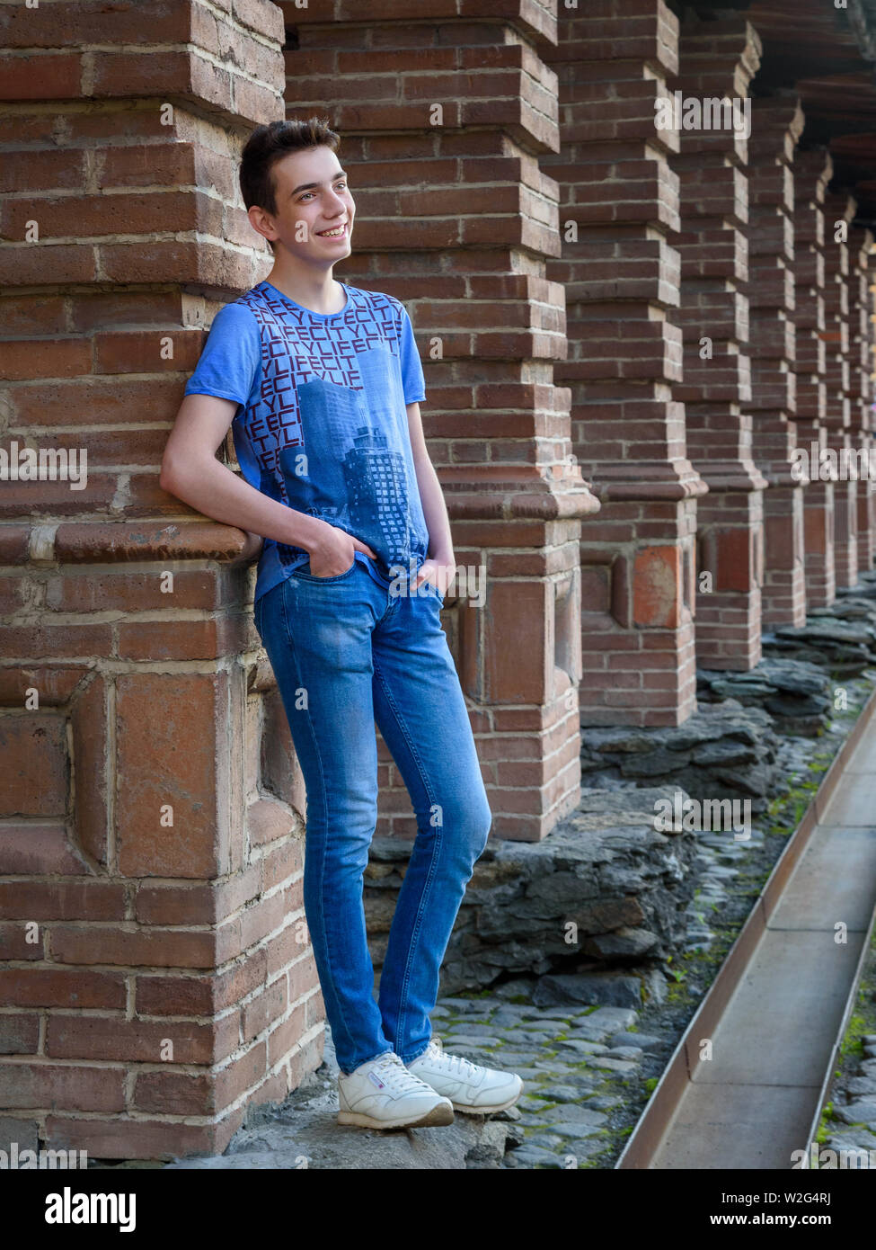 Teenage boy near brick columns on the street Stock Photo - Alamy