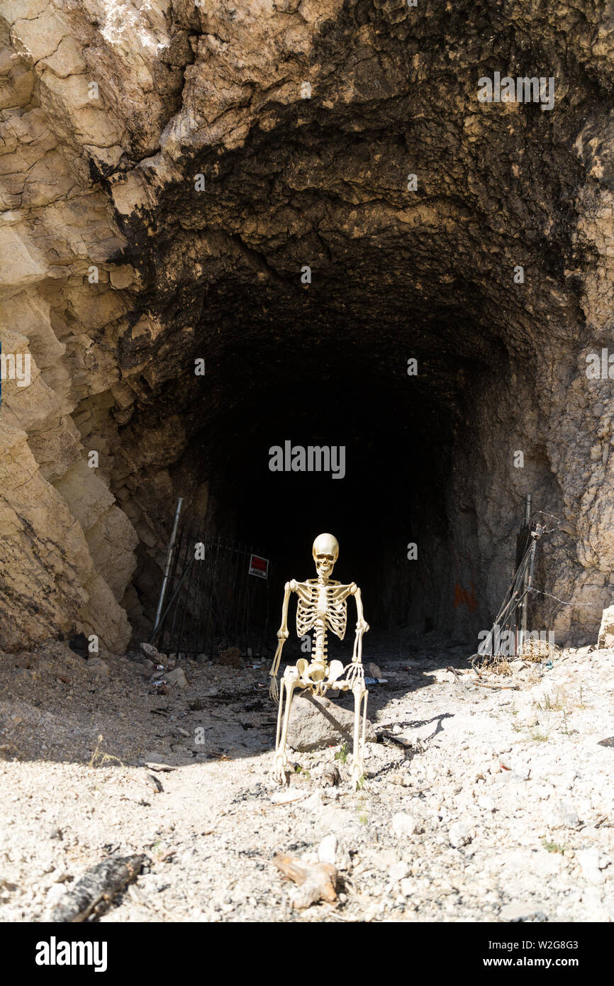 Skeleton in the mouth of a dark hole in the ground Stock Photo - Alamy