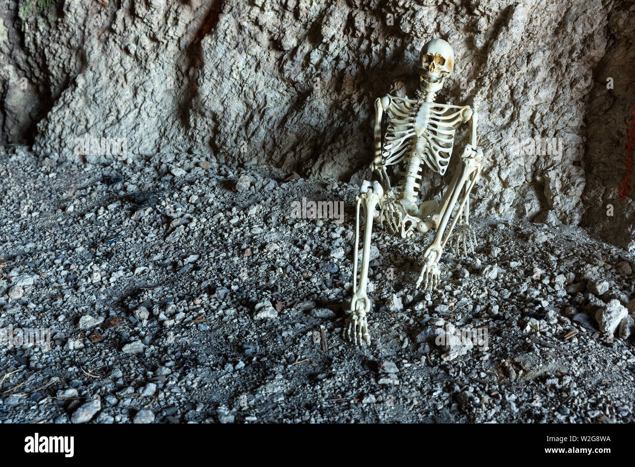 Skeleton in a dark cave in the ground lying on rocks Stock Photo - Alamy