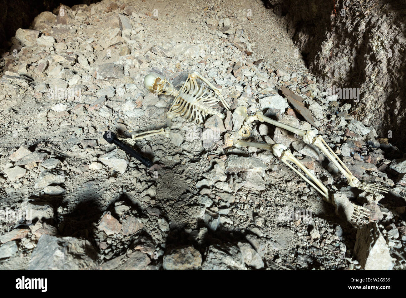 Skeleton in a dark cave in the ground lying on rocks Stock Photo - Alamy