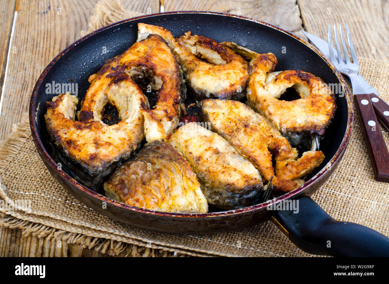 Old frying pan with fried fish on wooden table Stock Photo - Alamy