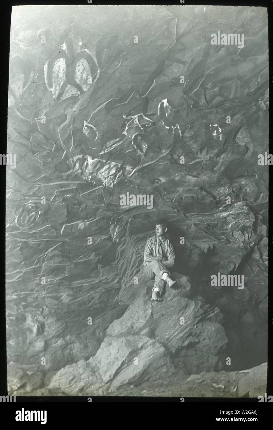 Chilean boy sitting with his legs crossed, on a rock inside a cave ...