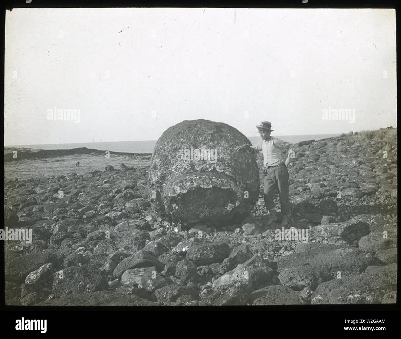 Chilean boy standing beside a large round stone used as part of a moai ...