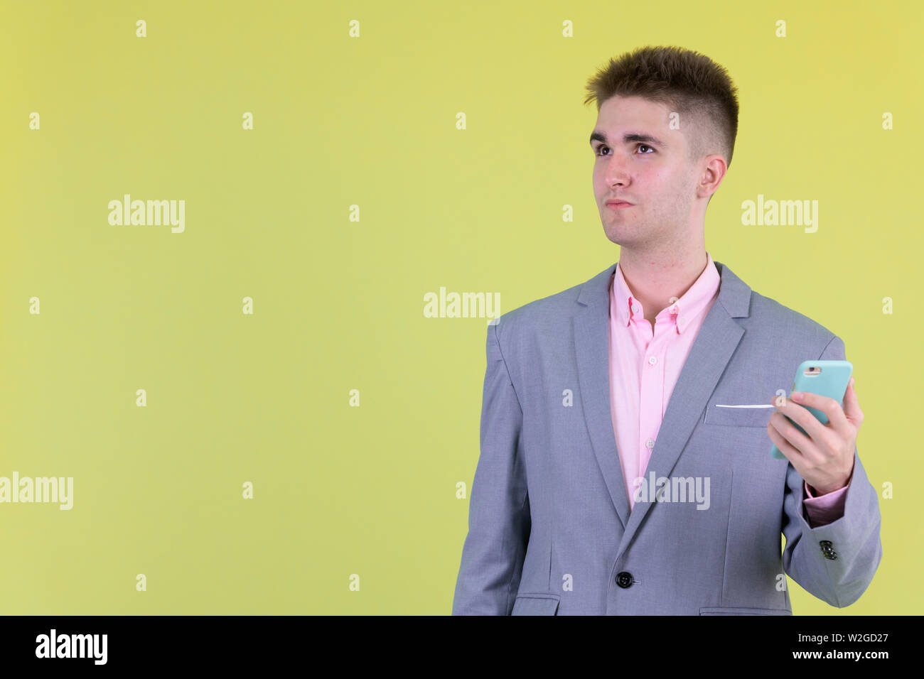 Young handsome businessman thinking while using phone Stock Photo - Alamy