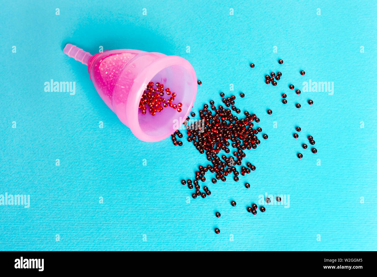 pink menstrual cup with a drop of blood on a blue background. Concept ...