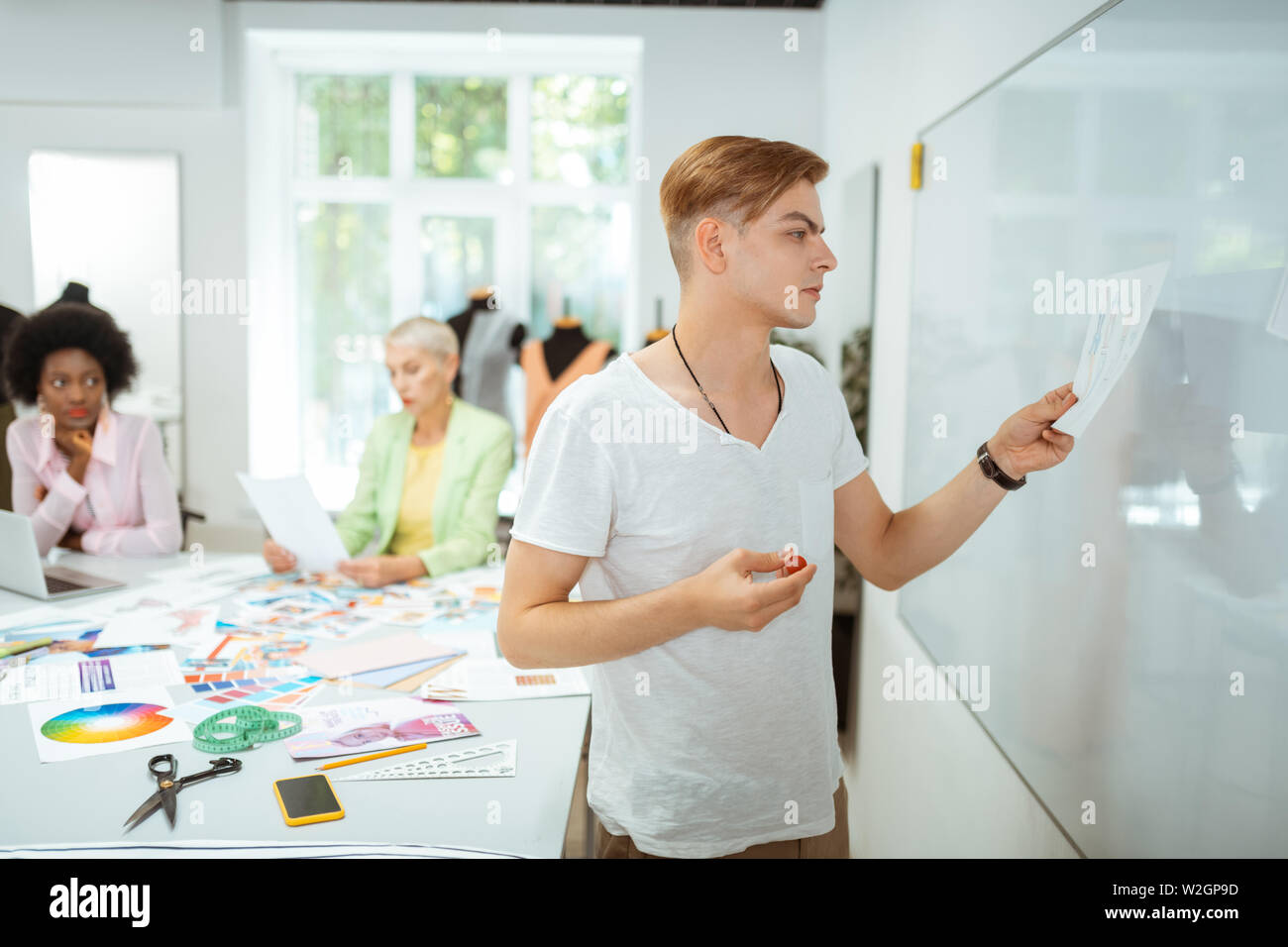 In a workshop. Side view portrait of a handsome busy man standing in ...