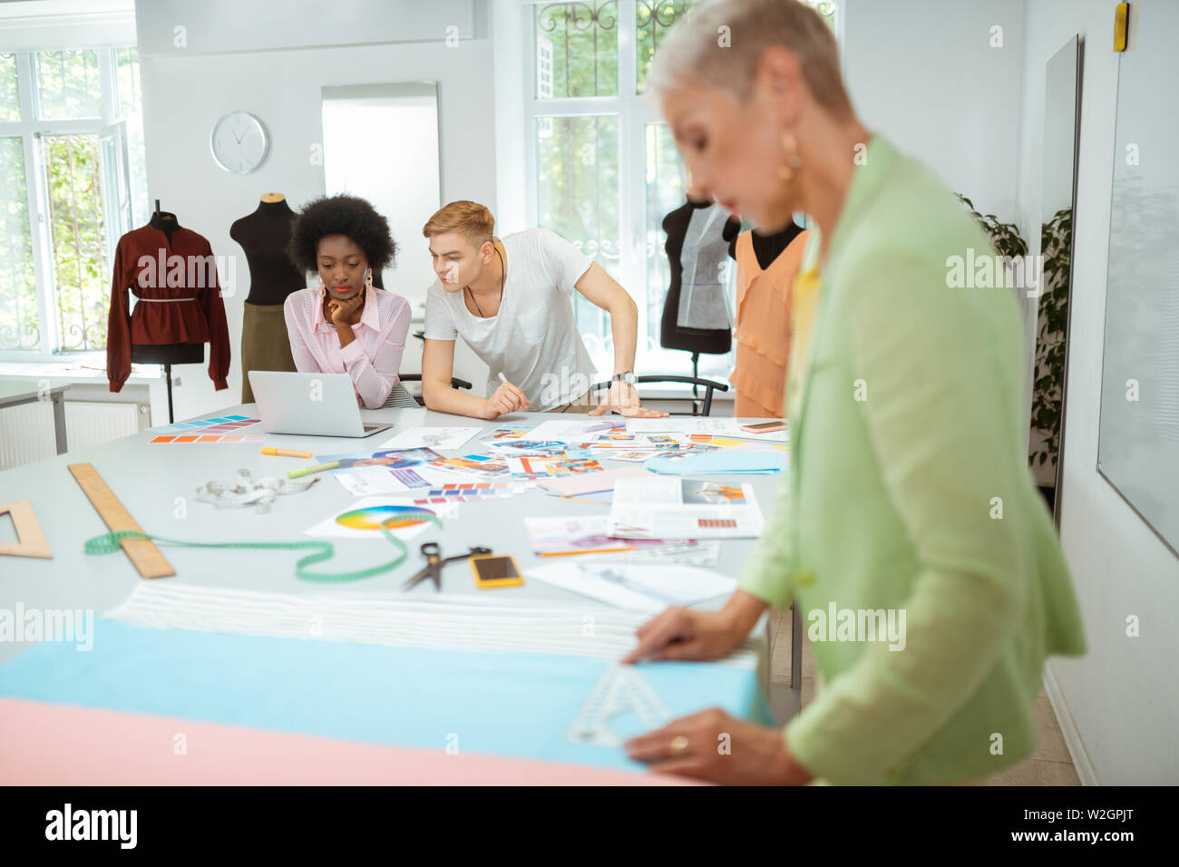 Working together. Three professional fashion designers working at a ...