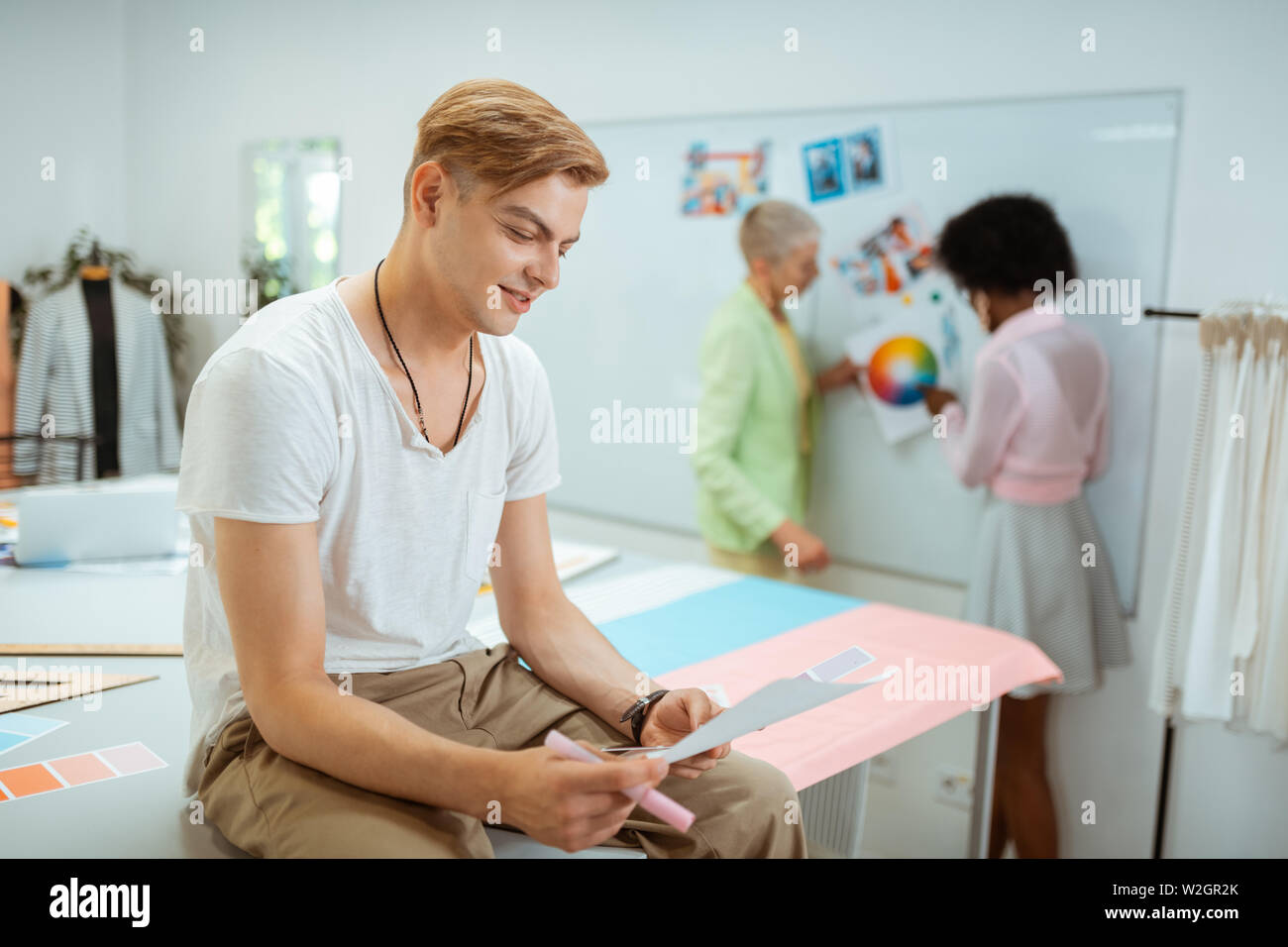 On the cutting table. Handsome young man sitting on the cutting table ...
