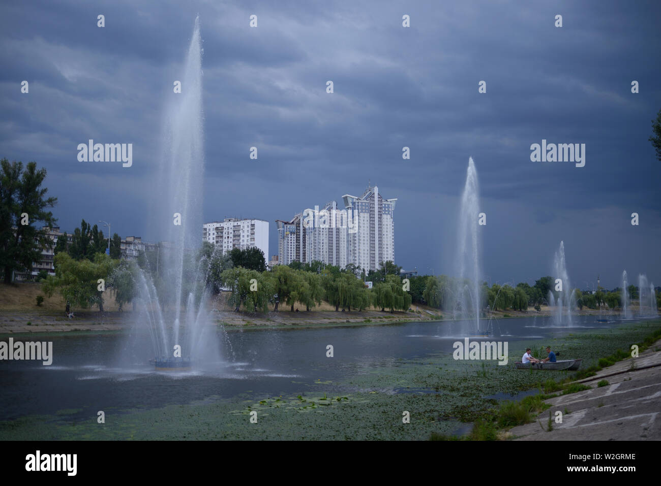 Evening view of the Rusanovka canal, men rowing boat, fountains working ...
