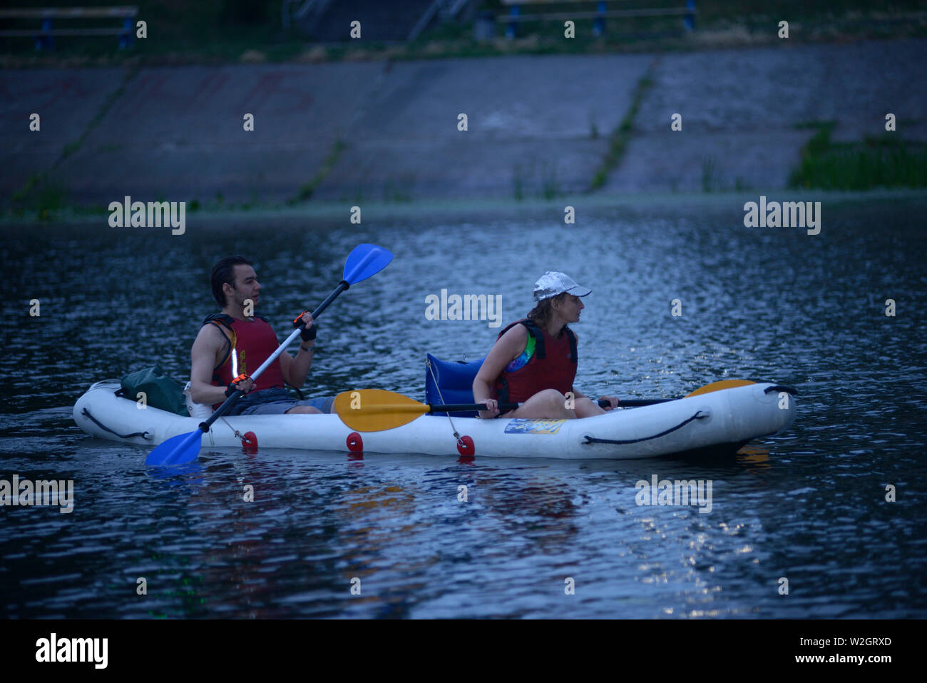 Man and woman rowing canoe in the evening. June 5, 2019. Rusanovka ...