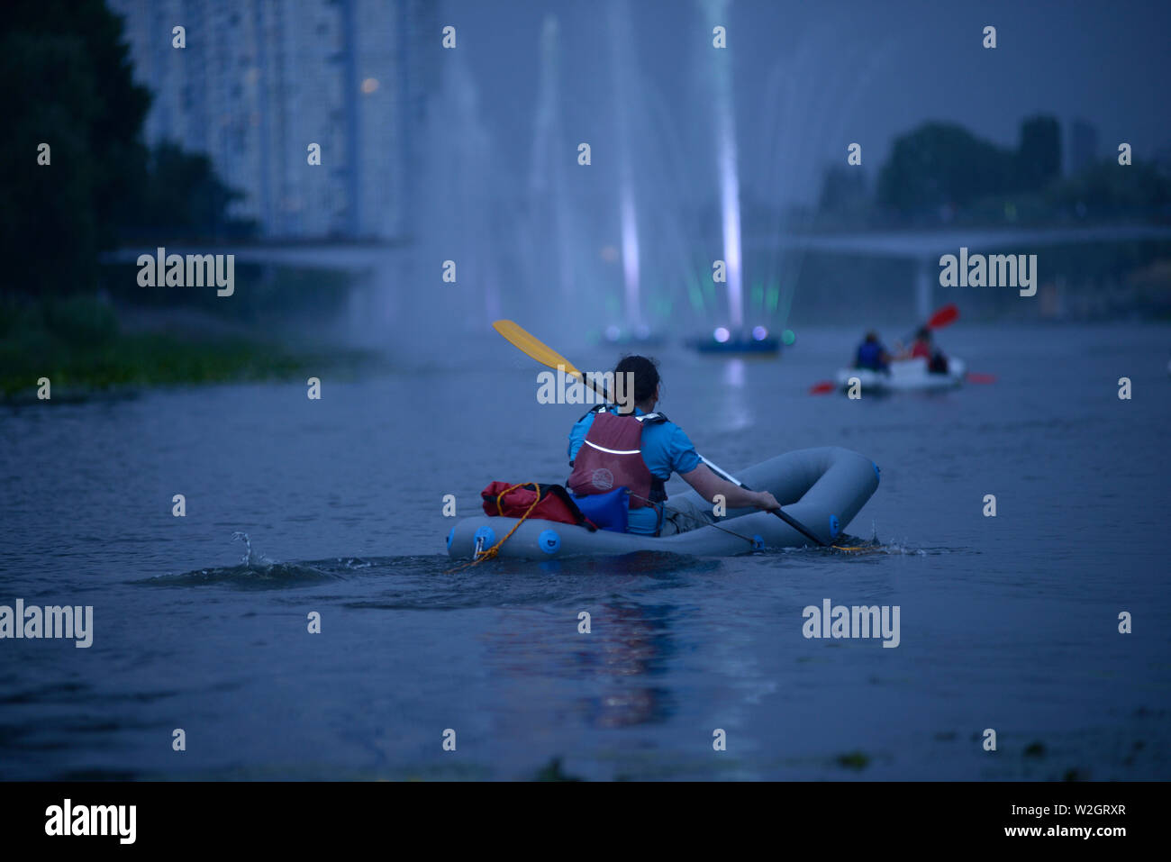 Evening view of the Rusanovka canal, people rowing canoes, illuminated ...