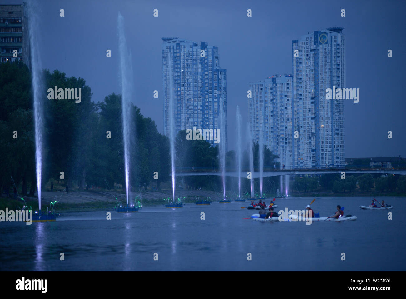 Evening view of the Rusanovka canal, people rowing canoes, illuminated ...