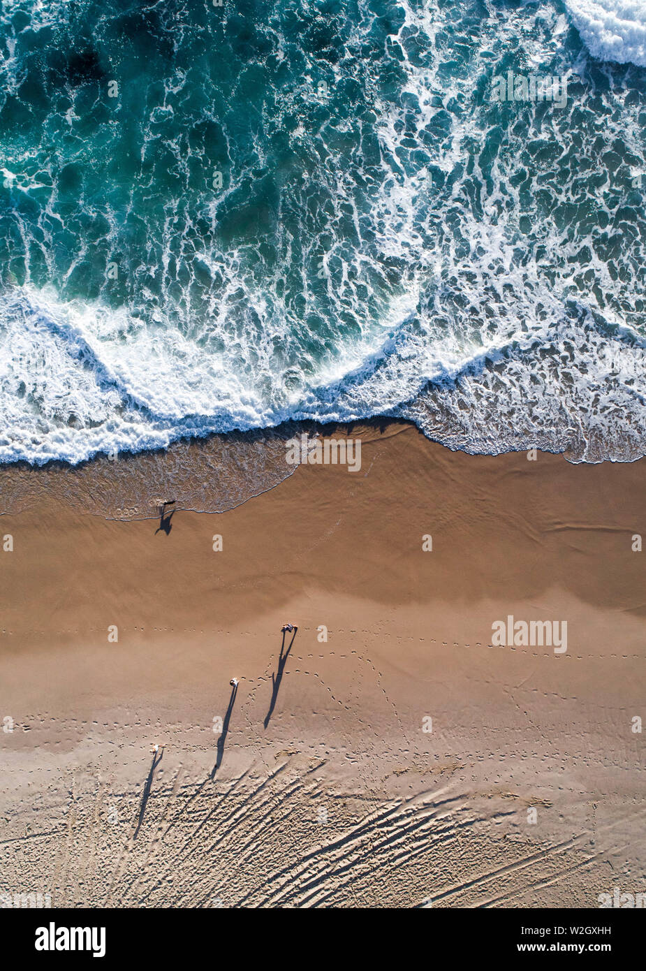 Aerial of people walking on a beach at sunrise with beautiful sand ...