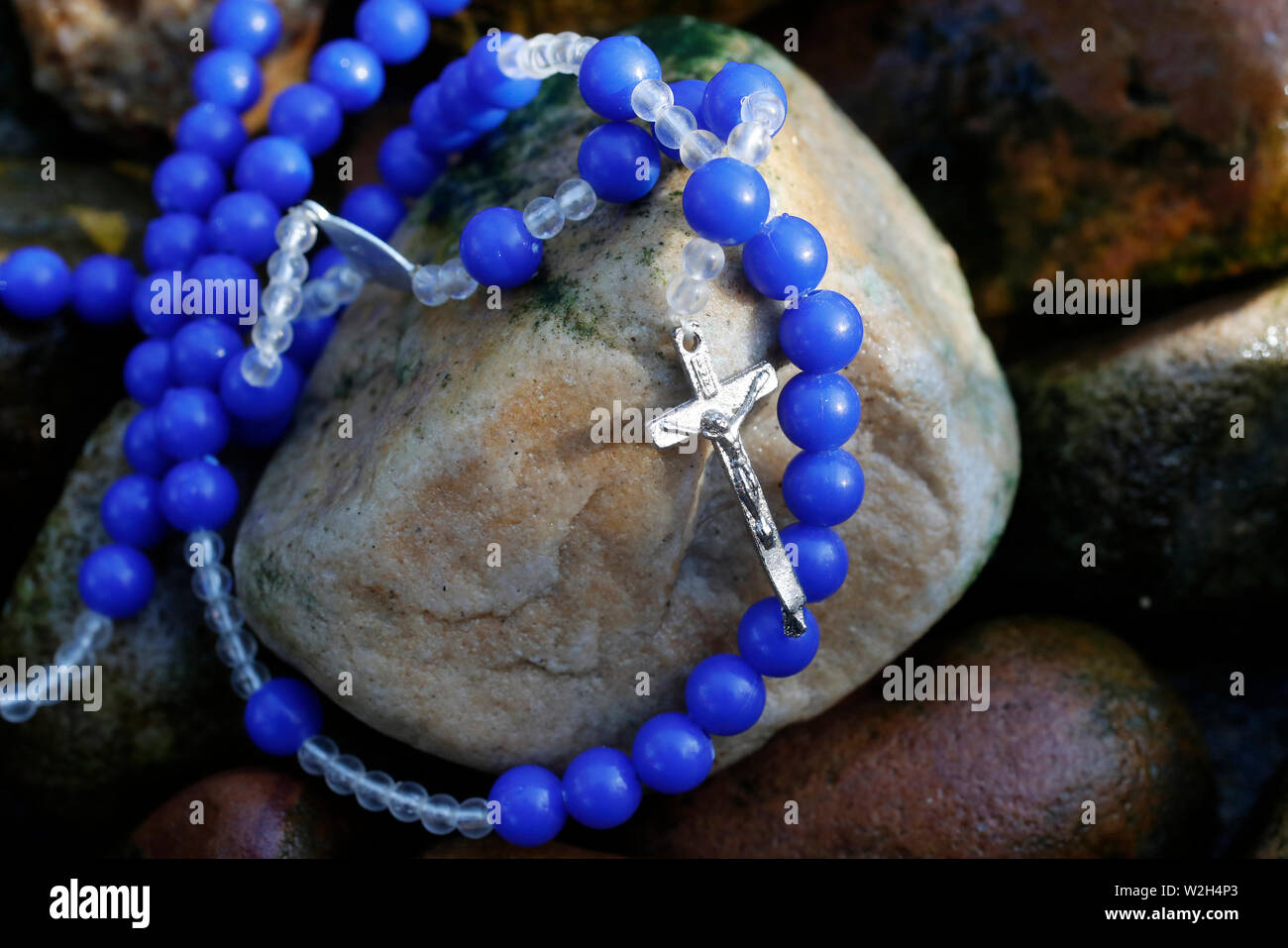 Blue christain rosary on a river stone Stock Photo - Alamy