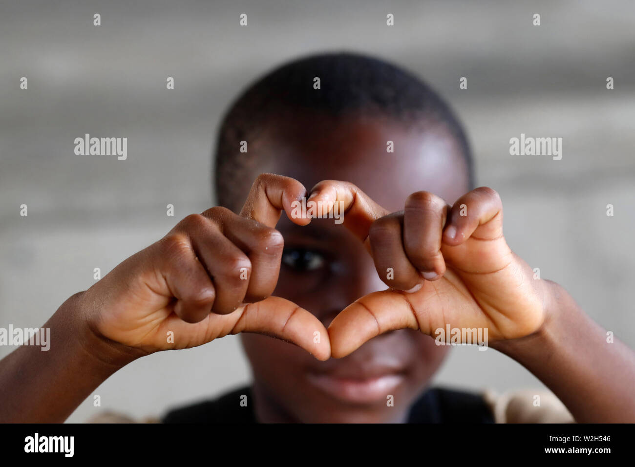 African primary school. Boy making hands gesture love or heart sign ...