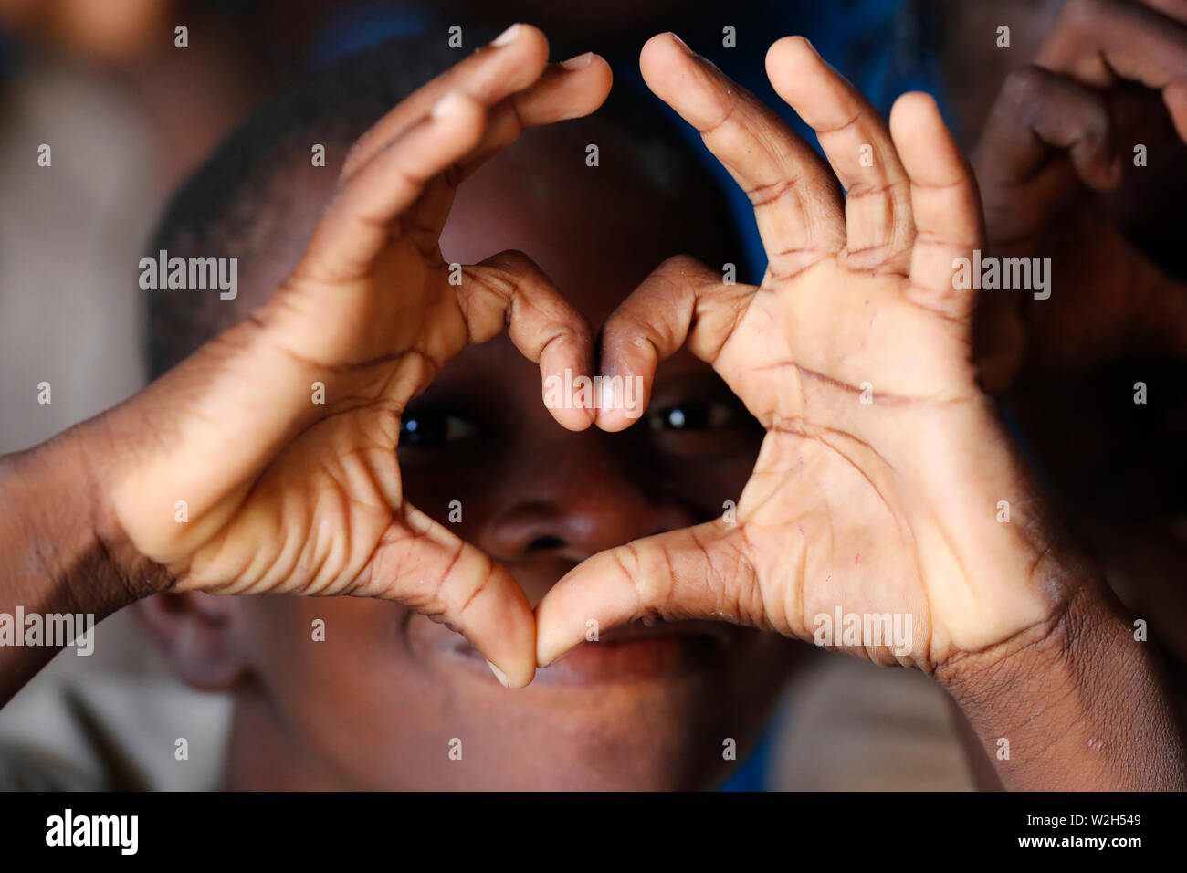 African primary school. Boy making hands gesture love or heart sign ...