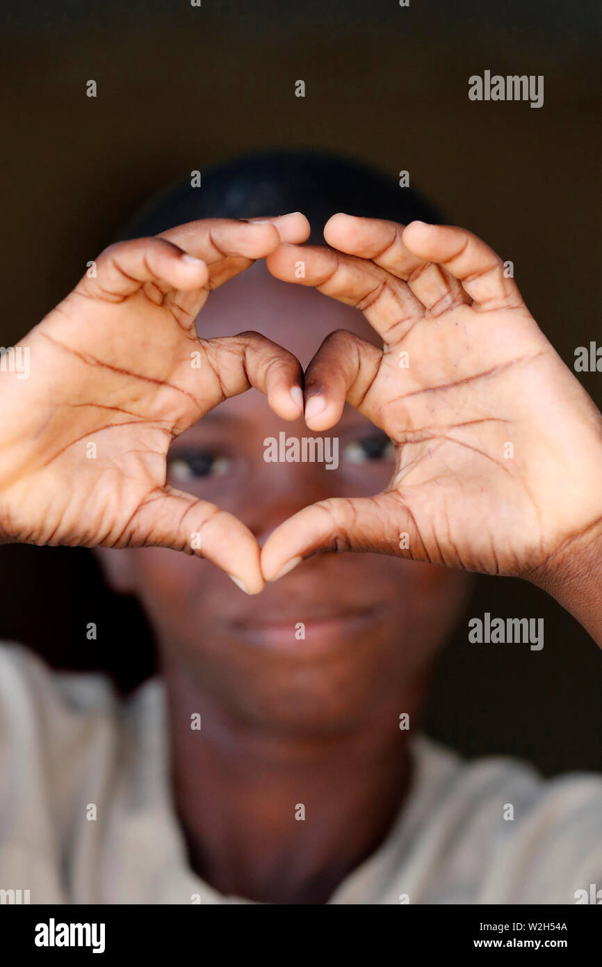 African primary school. Boy making hands gesture love or heart sign ...