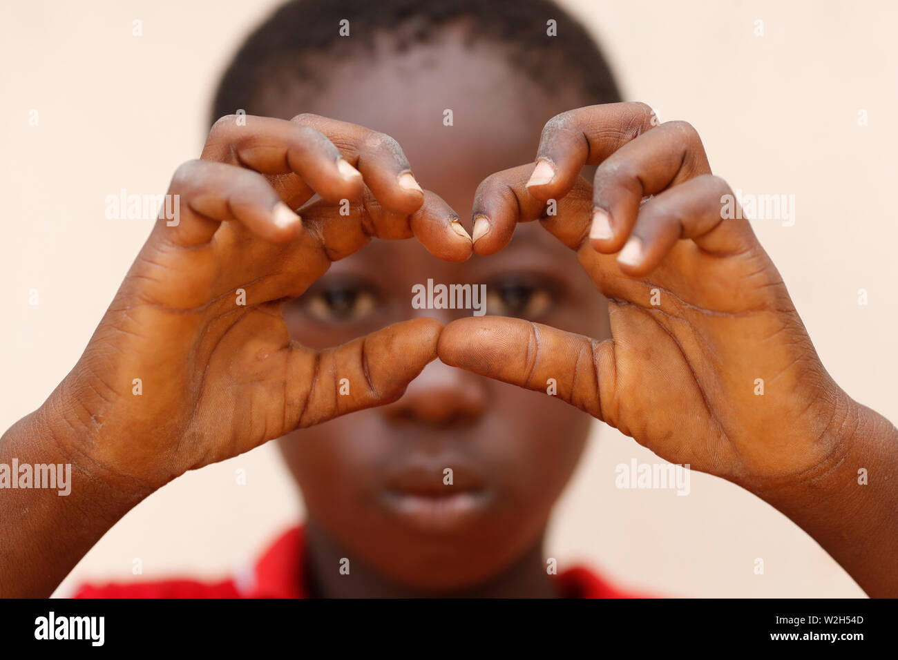 African primary school. Boy making hands gesture love or heart sign ...