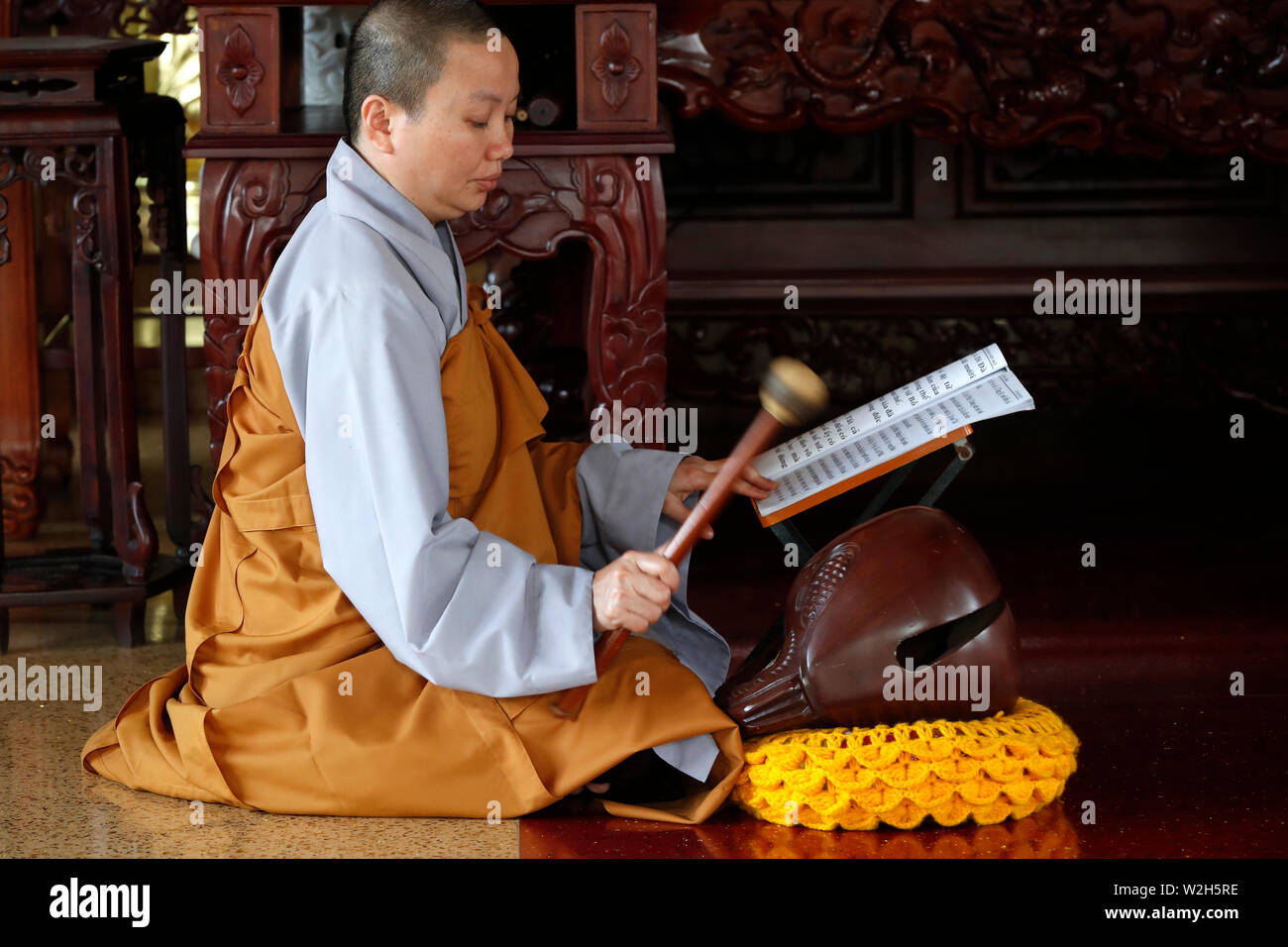 Buddhist ceremony at temple. Monk playing on a wooden fish (percussion ...