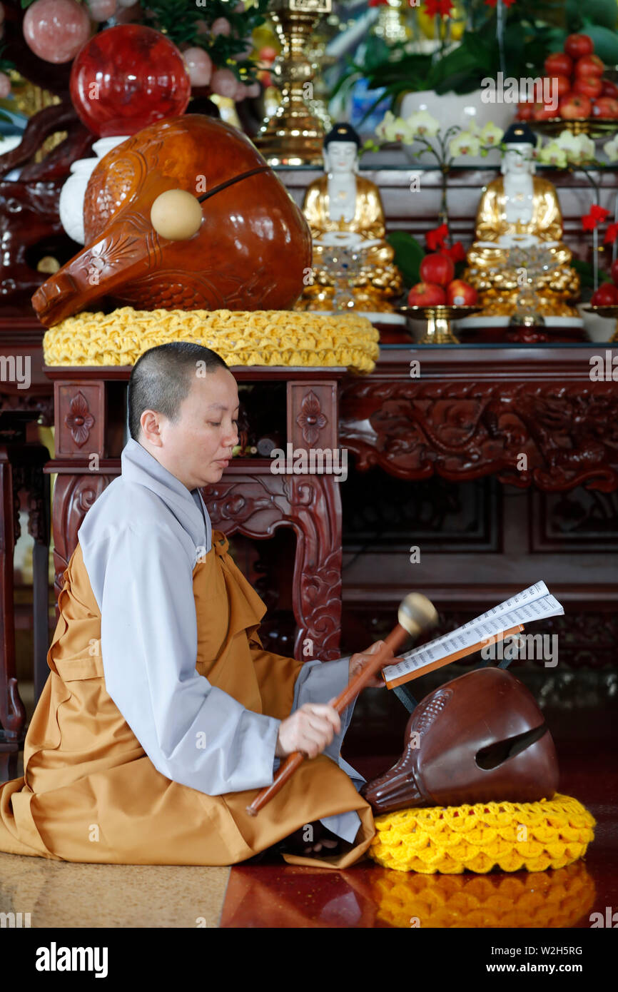 Buddhist ceremony at temple. Monk playing on a wooden fish (percussion ...