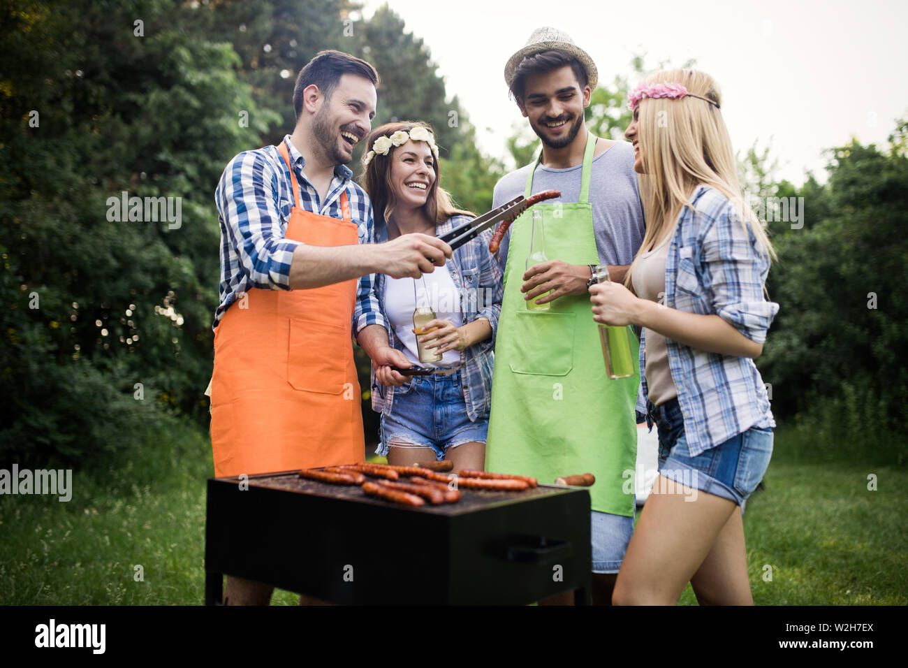 Group of friends making a barbecue together outdoors in the nature ...