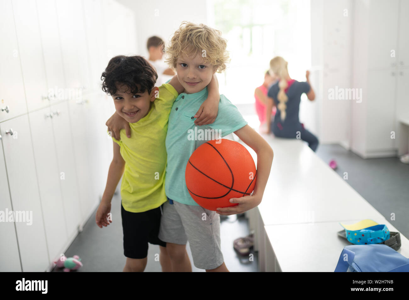 Two friends hugging standing in school changing room Stock Photo - Alamy