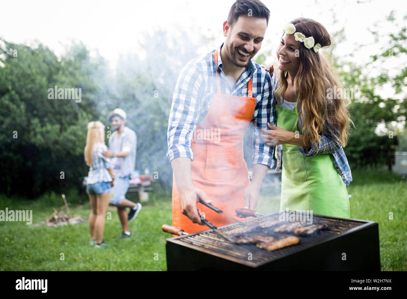 Happy group of friends making a barbecue together outdoors in the ...