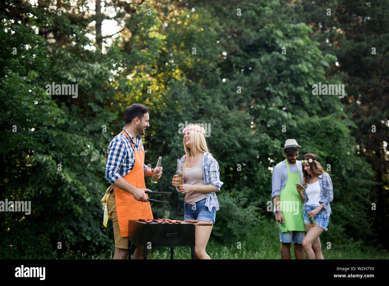 Group of friends making a barbecue together outdoors in the nature ...