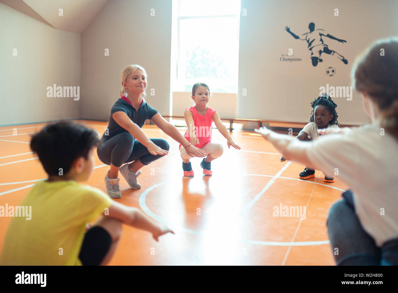 School children bending knees at sports lesson Stock Photo - Alamy