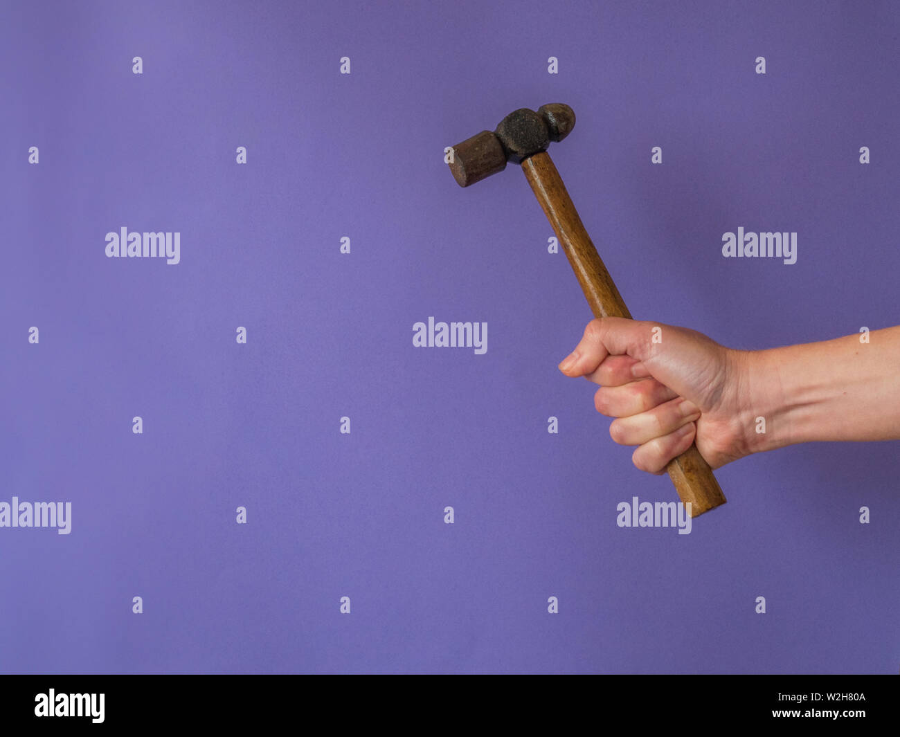 Hand with hammer on purple background with copy space Stock Photo - Alamy