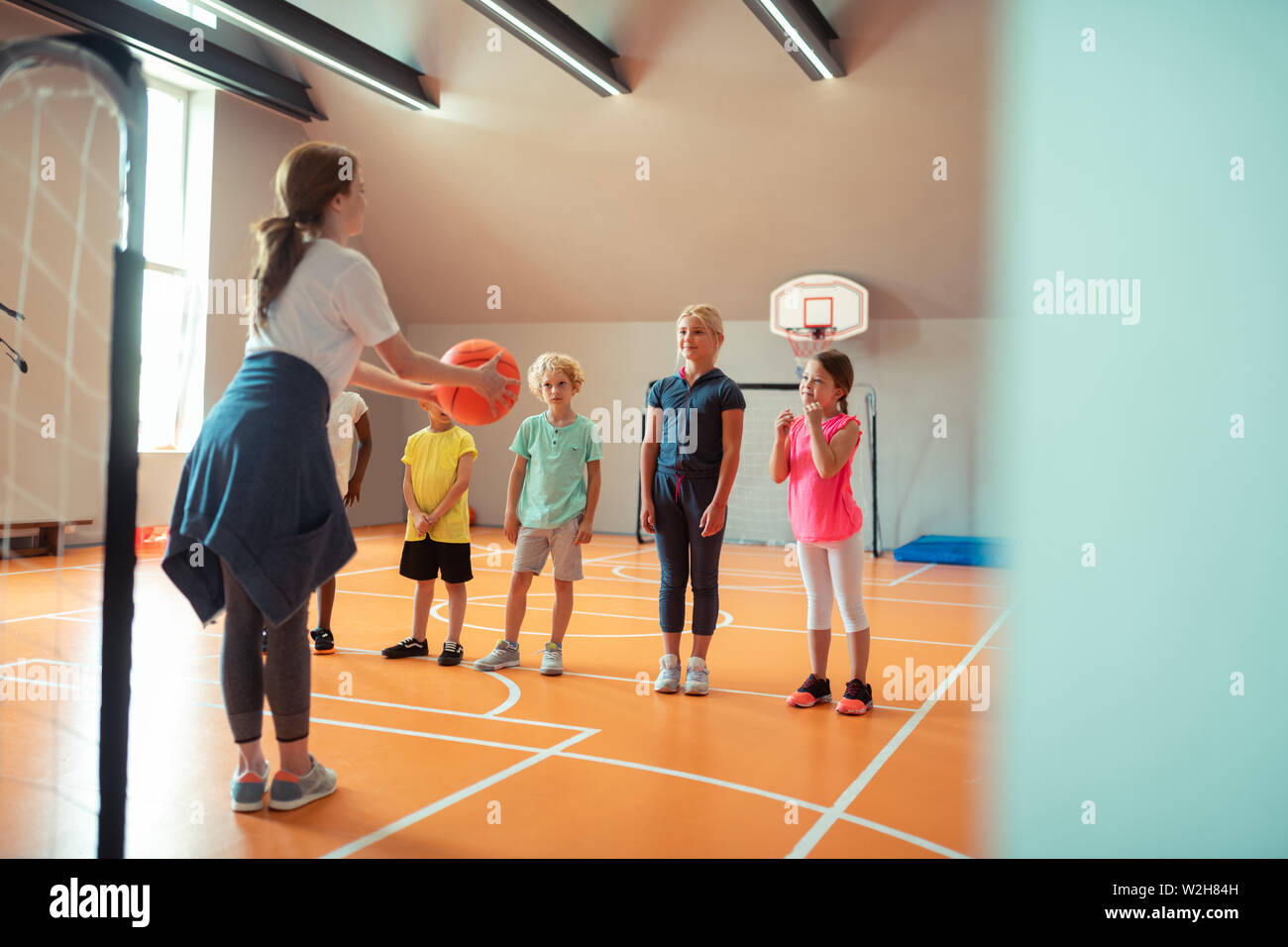 Coach teaching her pupils how to play ball Stock Photo - Alamy