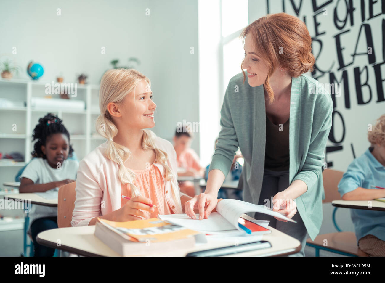Smiling teacher explaining the task to a school girl Stock Photo - Alamy